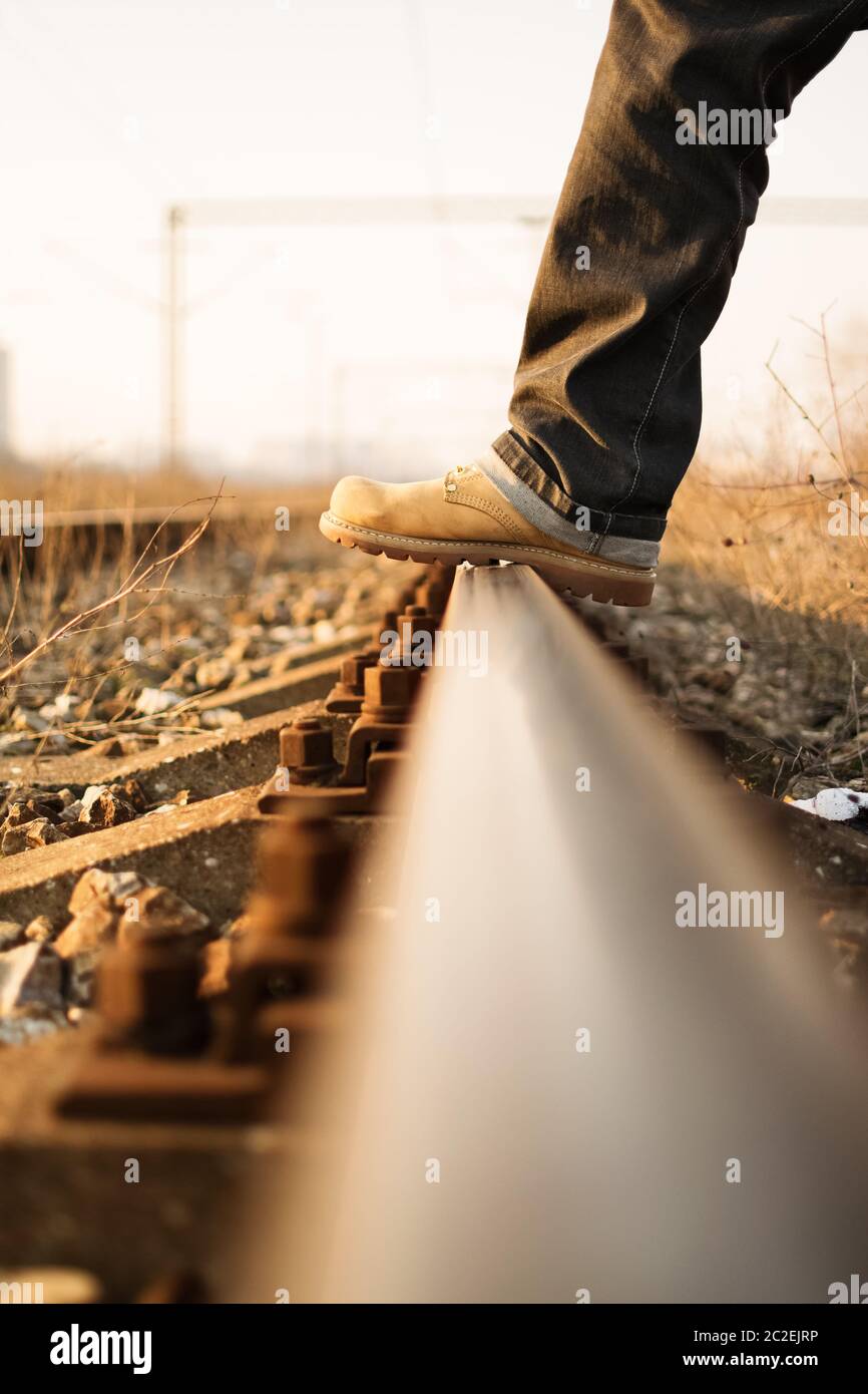 Time for a new journey. Man's foot stepping over train tracks Stock ...