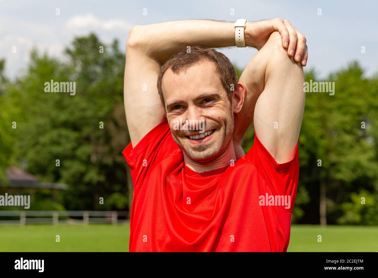 Young handsome sportsman is doing stretching exercises before workout ...