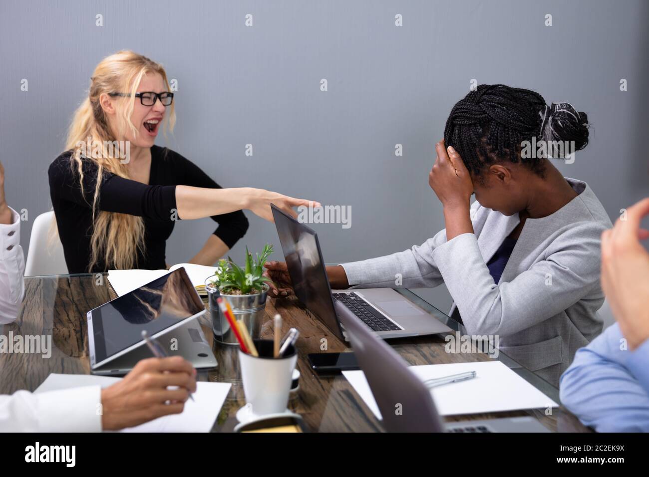 Furious Businesswoman Shouting At Female Employee Working On Laptop At ...