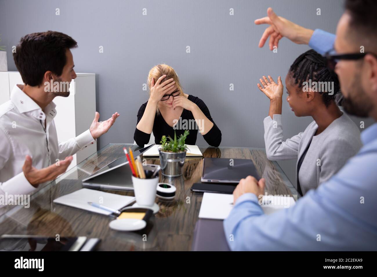 Upset Businesswoman Sitting With Young Aggressive Colleague In Meeting ...
