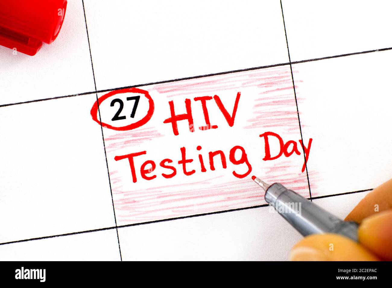 Woman fingers with pen writing reminder HIV Testing Day in calendar ...