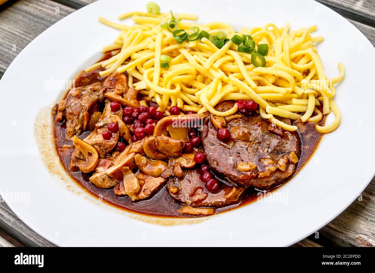 Roasted deer and wild boar with cranberries and spaetzle Stock Photo ...