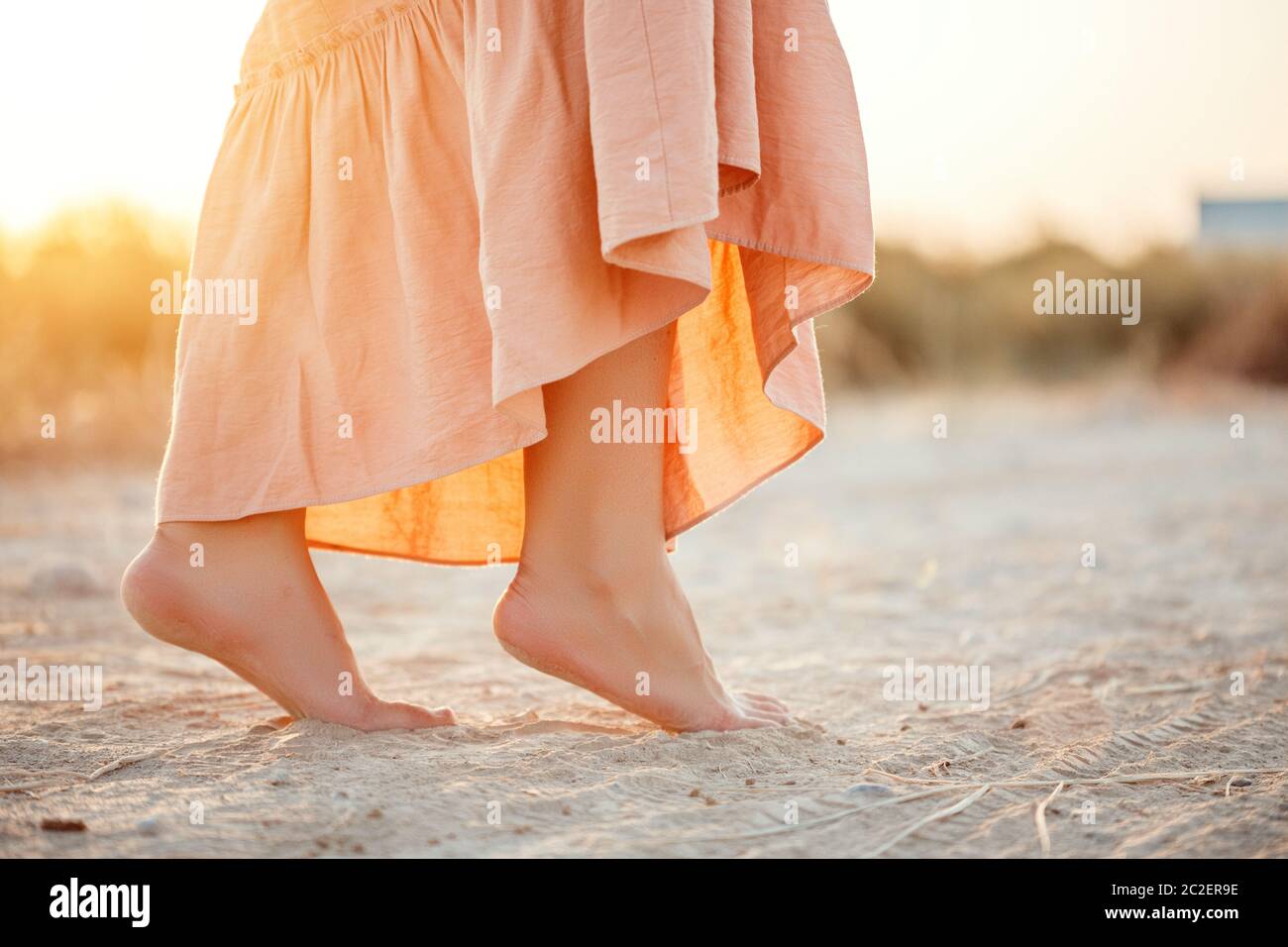 feet of a woman in a pink dress walking on the sand during sunset Stock ...