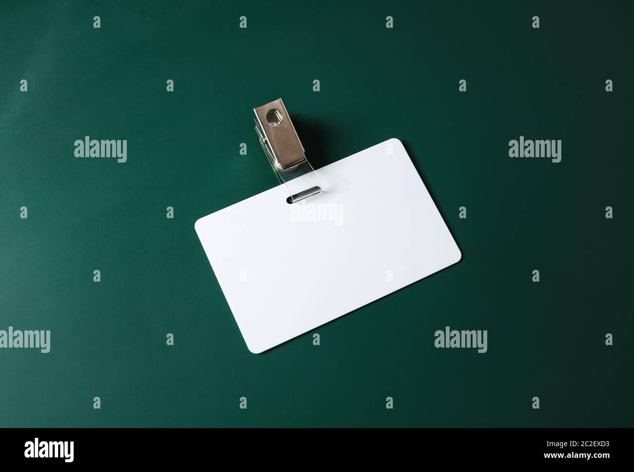 Blank ID card. White plastic badge on green blackboard background. Copy ...