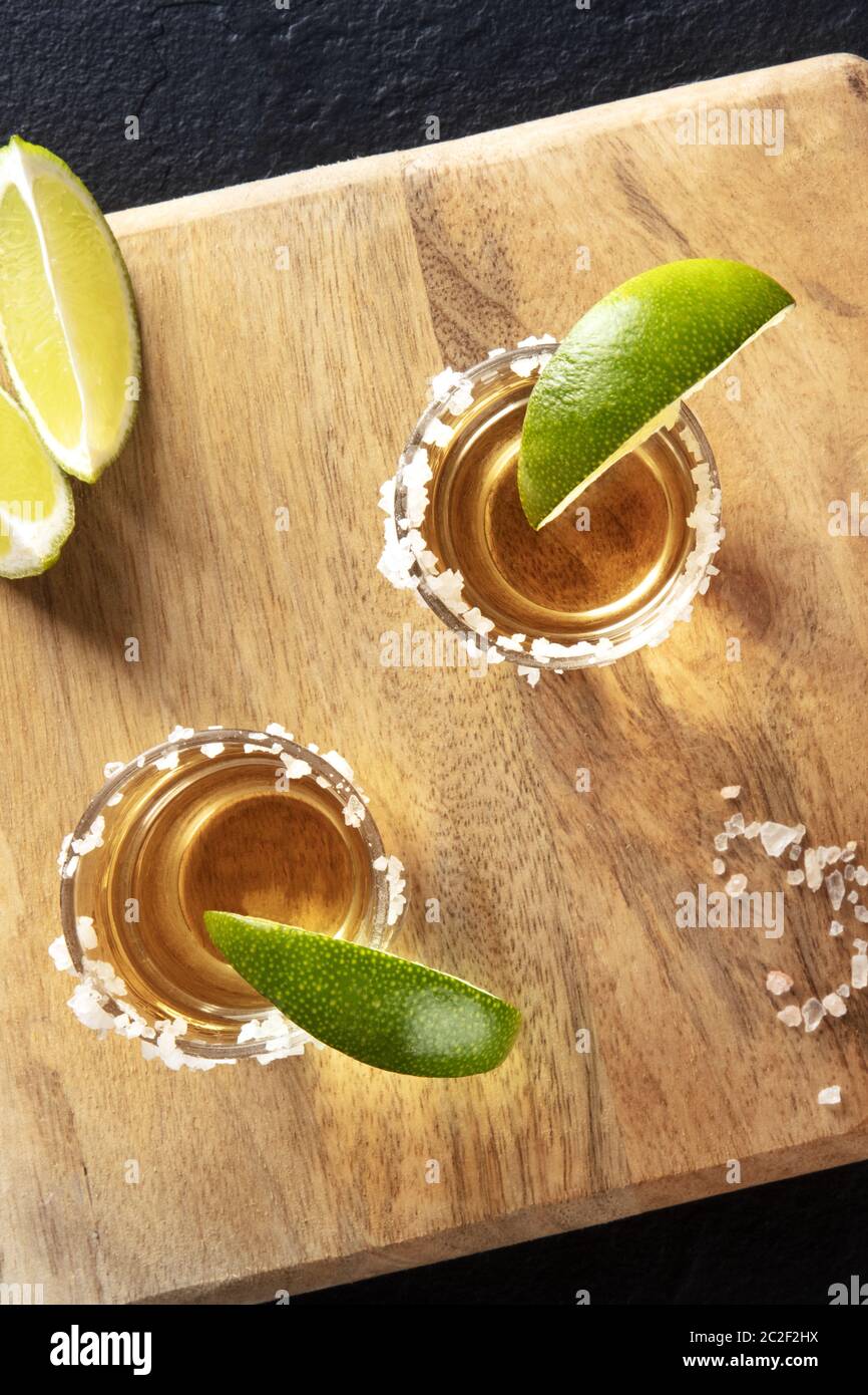 Golden tequila shots with salt rims and lime slices, overhead close-up ...