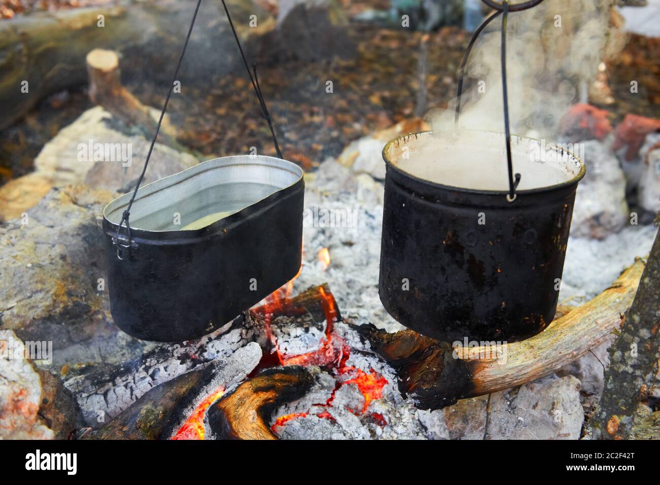 Boiling water in two pots above the fire Stock Photo - Alamy