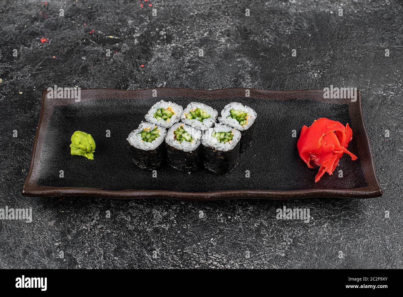 Japanese kappa maki roll of rice, nori and cucumber on a black ...