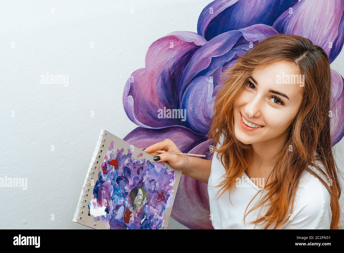 Artist. Designer. Young girl artist paints on a wall indoors. Interior ...