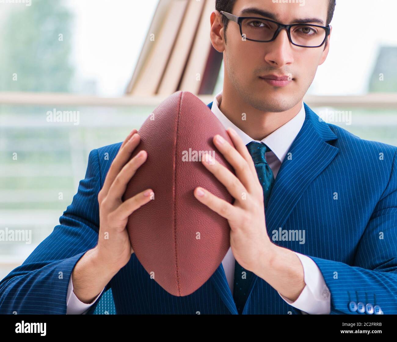 Businessman with american football in office Stock Photo - Alamy