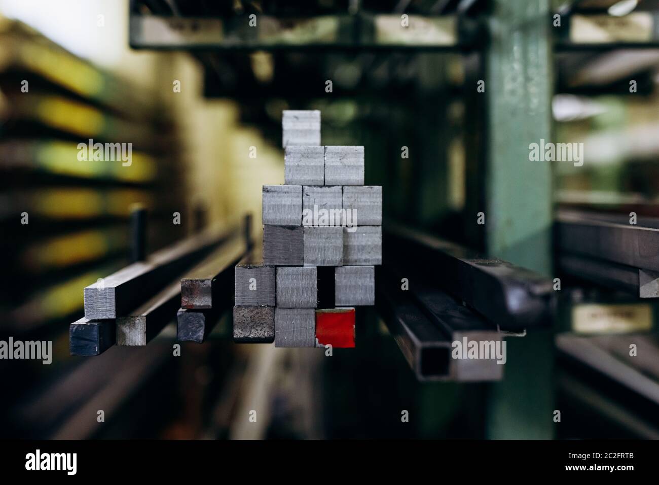 Steel square shaped rods in different sizes lying on storage shelves ...