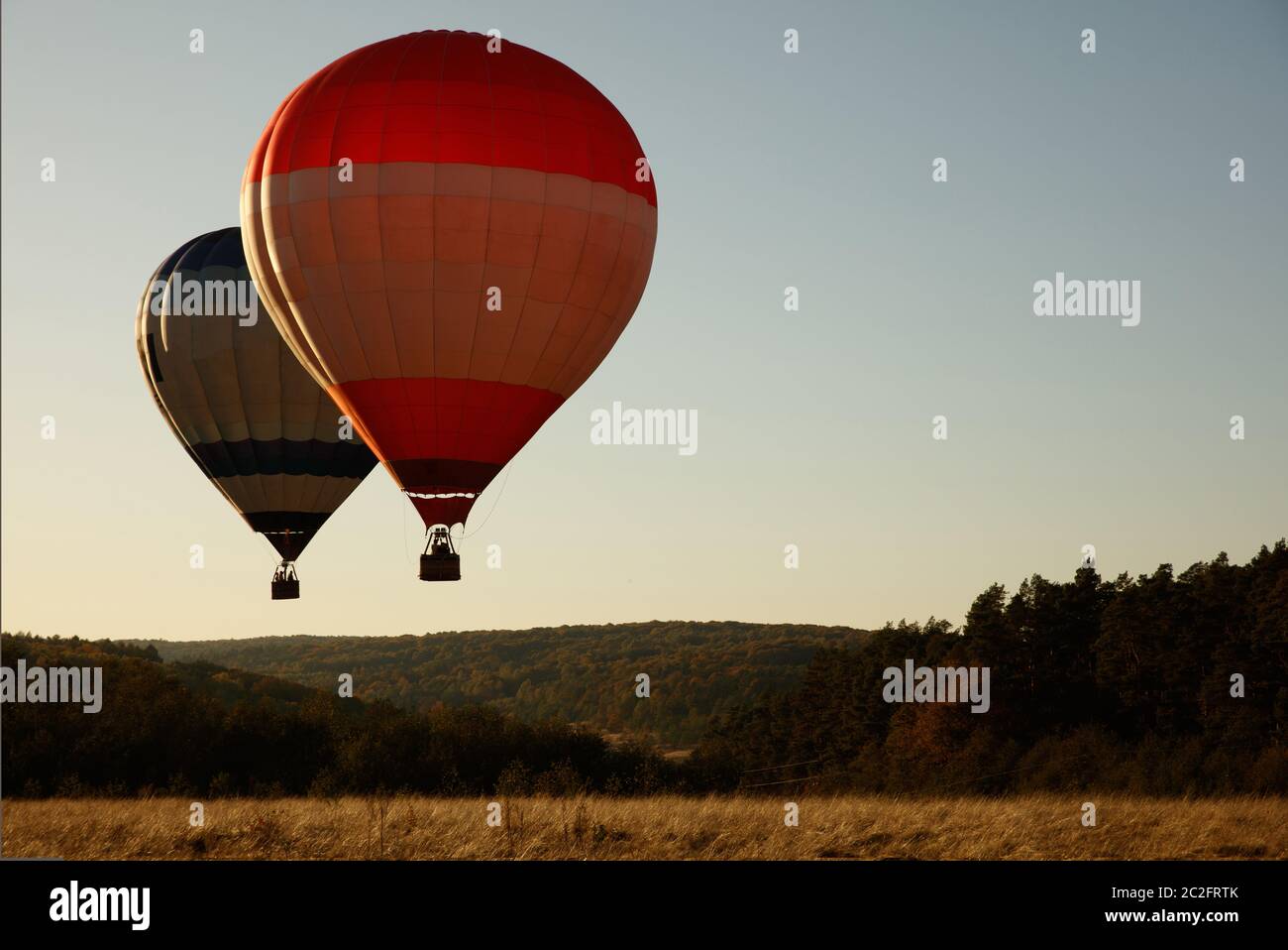 Group of two colorful air balloons flying over valley during summer ...