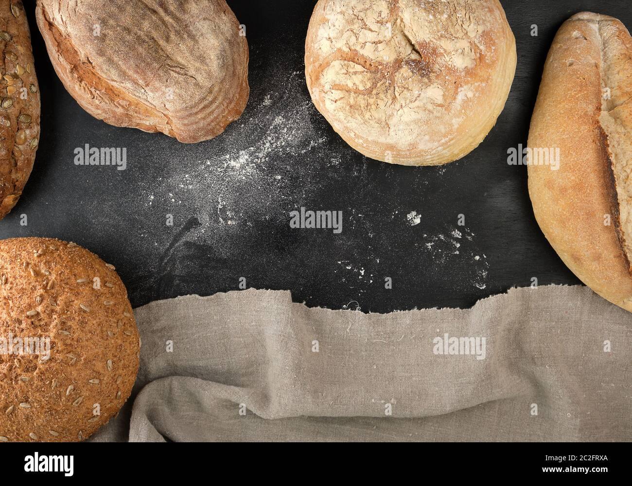 baked various loaves of bread on a black background, empty space, top ...