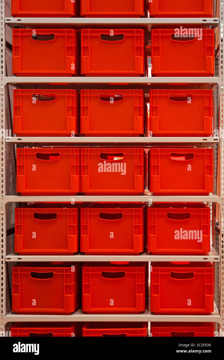 Shelf with red plastic crates in warehouse Stock Photo - Alamy