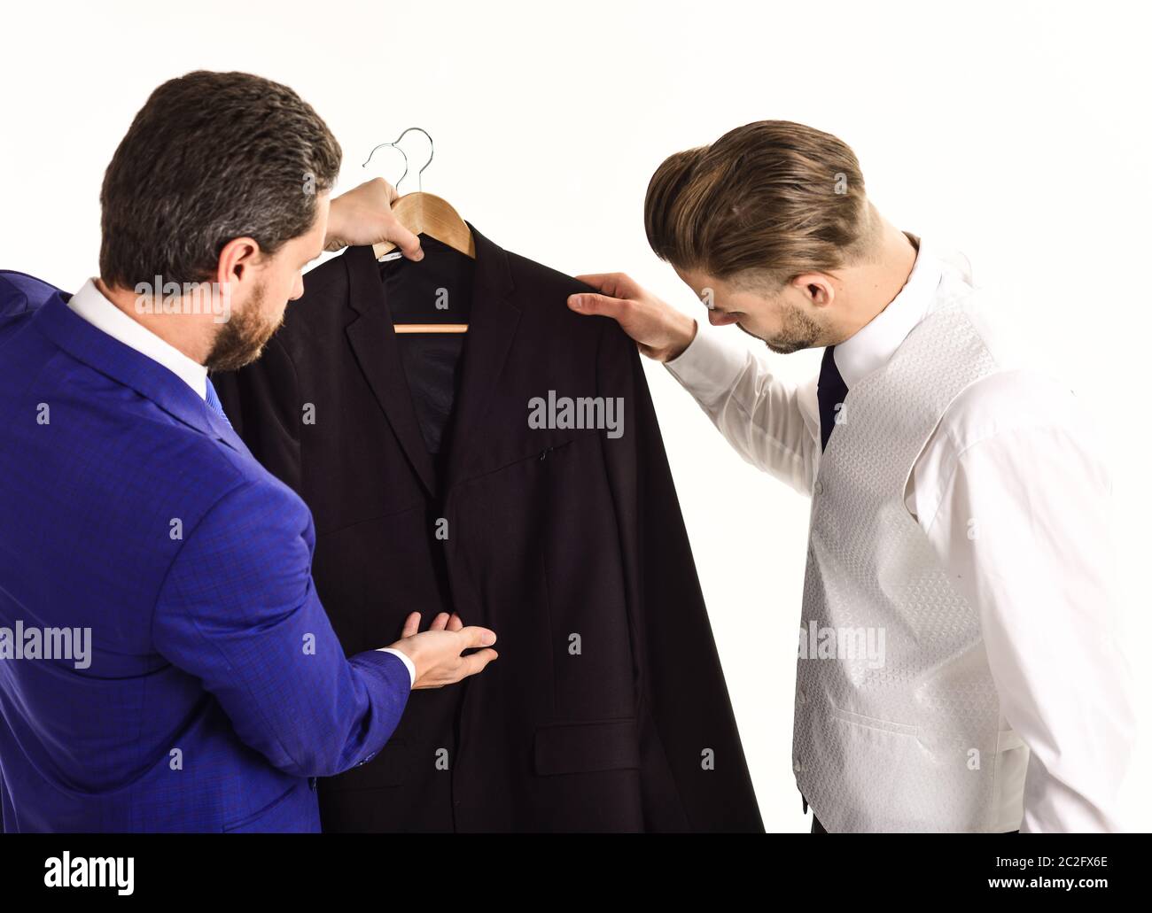 Shop assistant shows jacket to young man isolated on white background ...