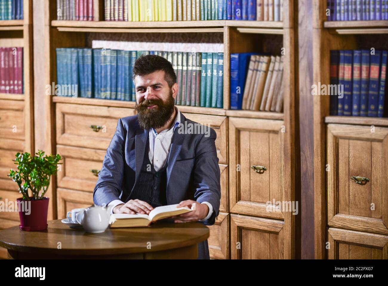 Man in classic suit sits in vintage interior, library, book shelves on ...