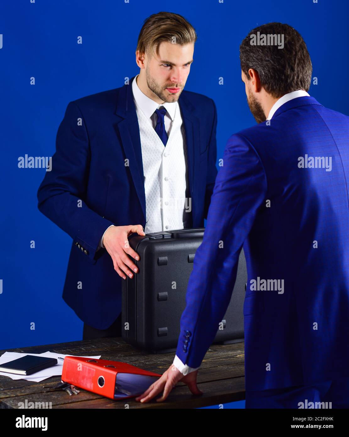 Men in suit or businessmen meet for handover of black briefcase and red ...