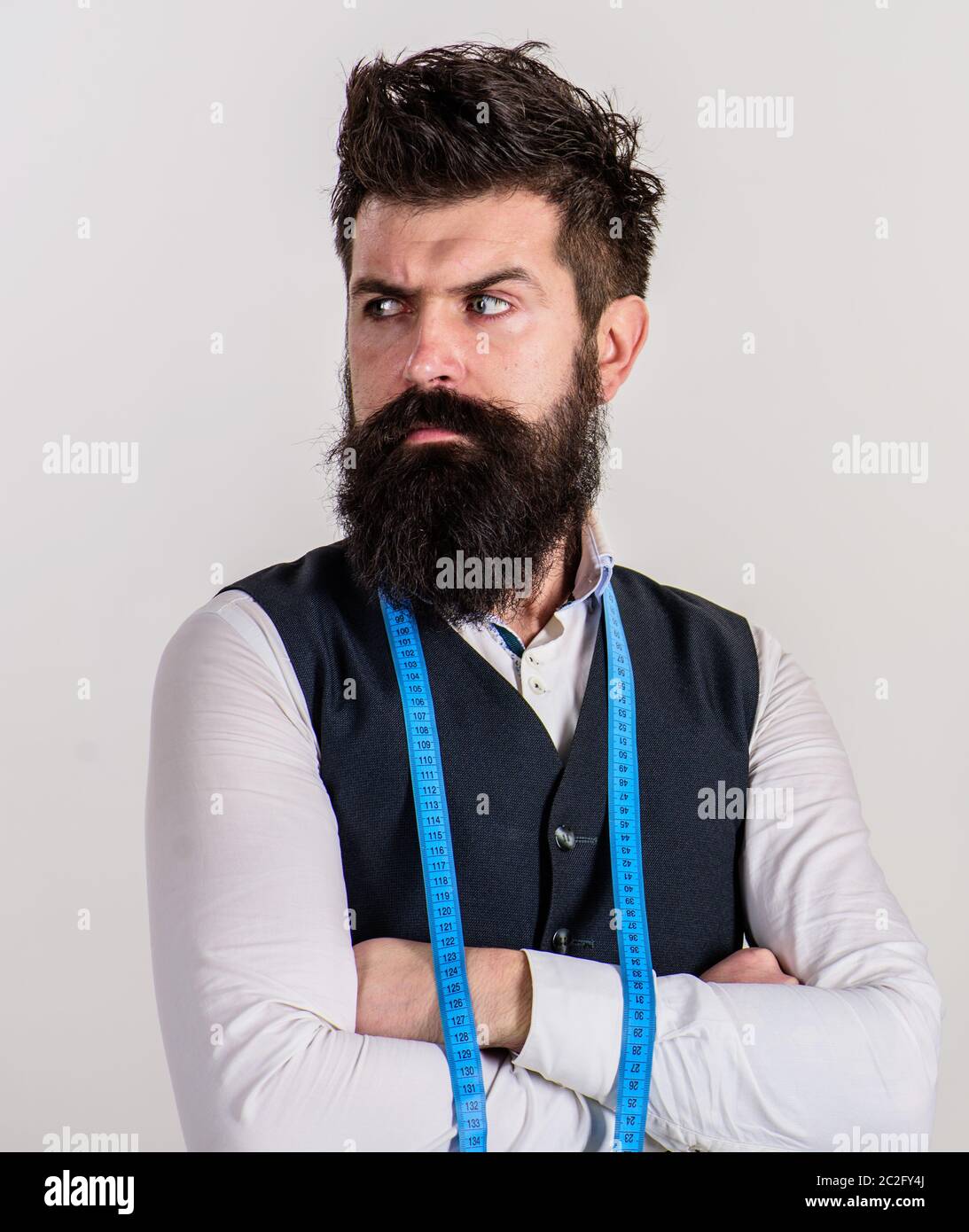 Macho in waistcoat and measuring tape around neck. Man with beard and ...