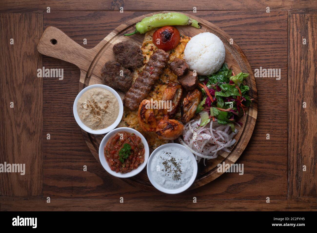 Mixed turkish kebab plate with rice, vegetables and dip sauces isolated ...