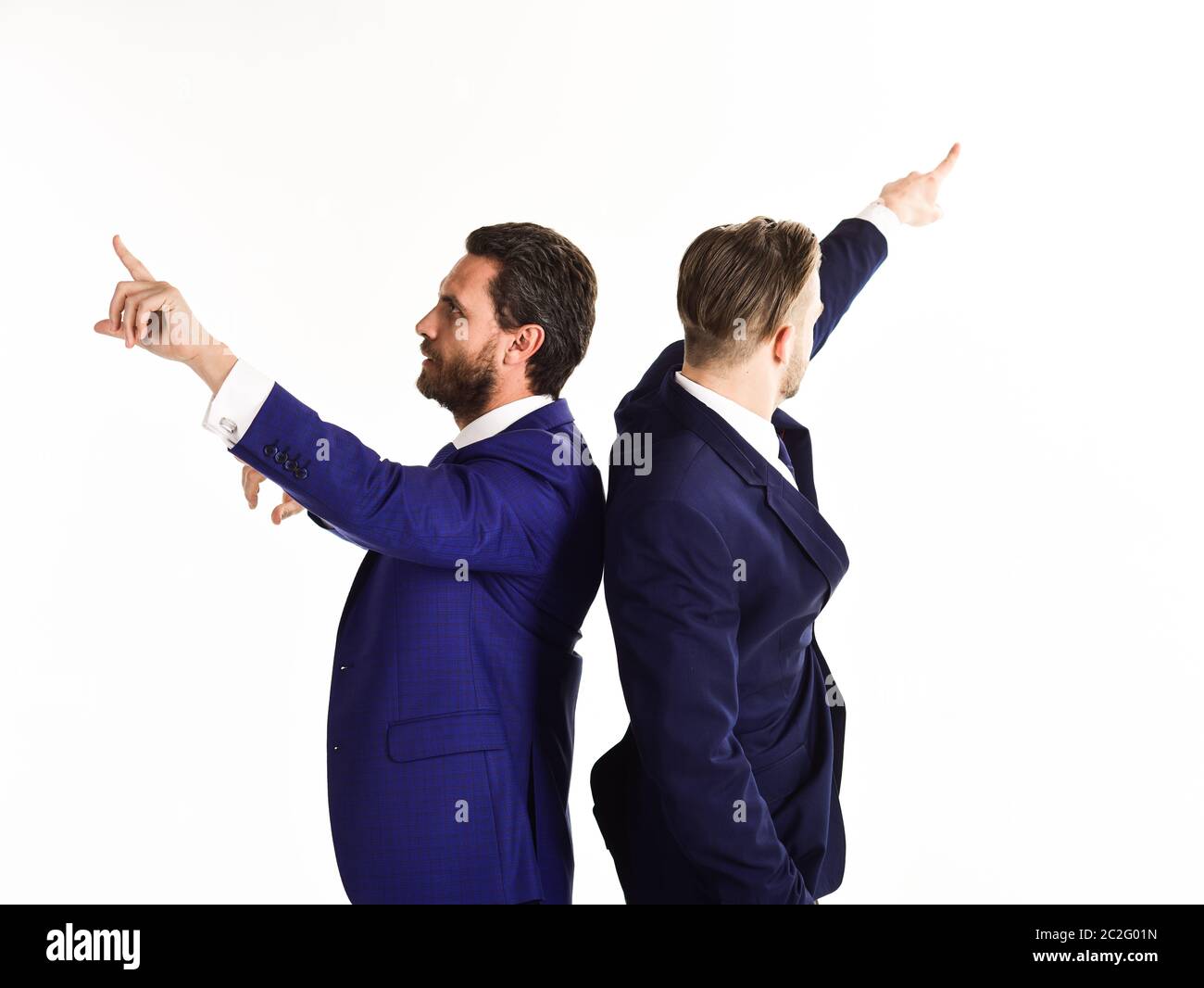Young businessmen pointing in two different directions at same time ...