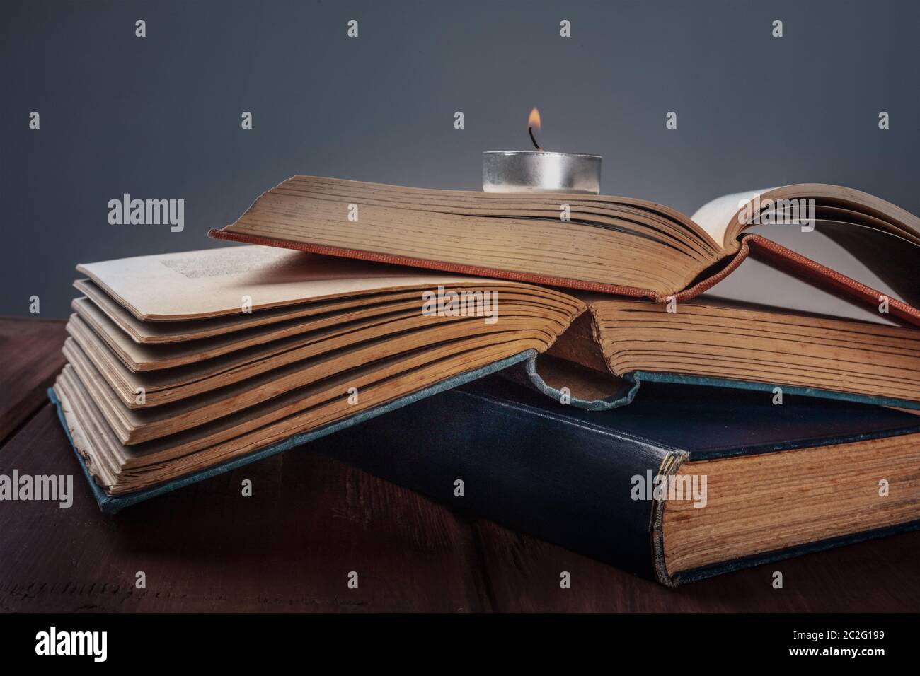 A stack of old books with a burning candle and a place for text ...