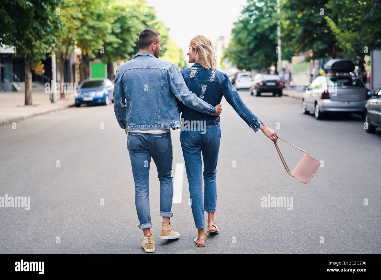 Back view of hugging couple walking away on the street Stock Photo - Alamy