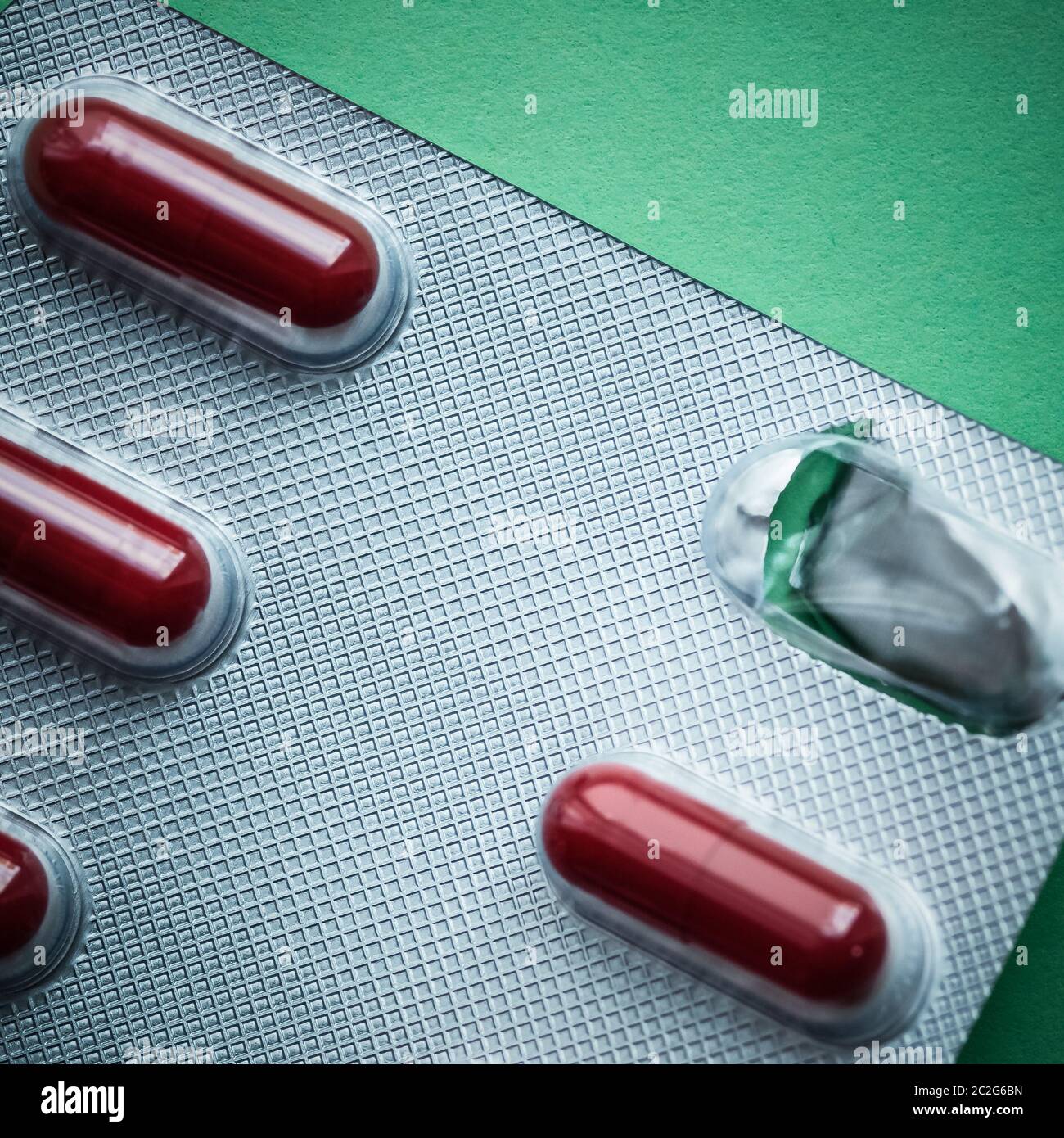 Blister with dark red tablets on a green background Stock Photo - Alamy
