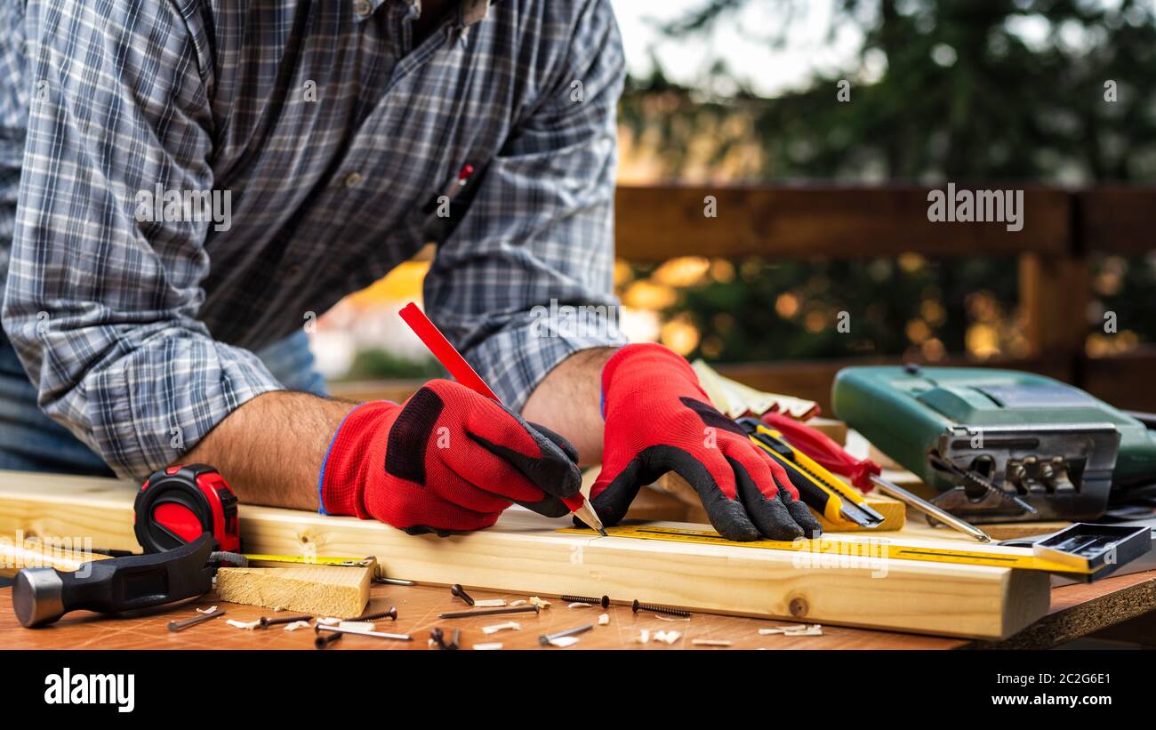 Adult carpenter craftsman wears protective gloves, with a pencil and ...