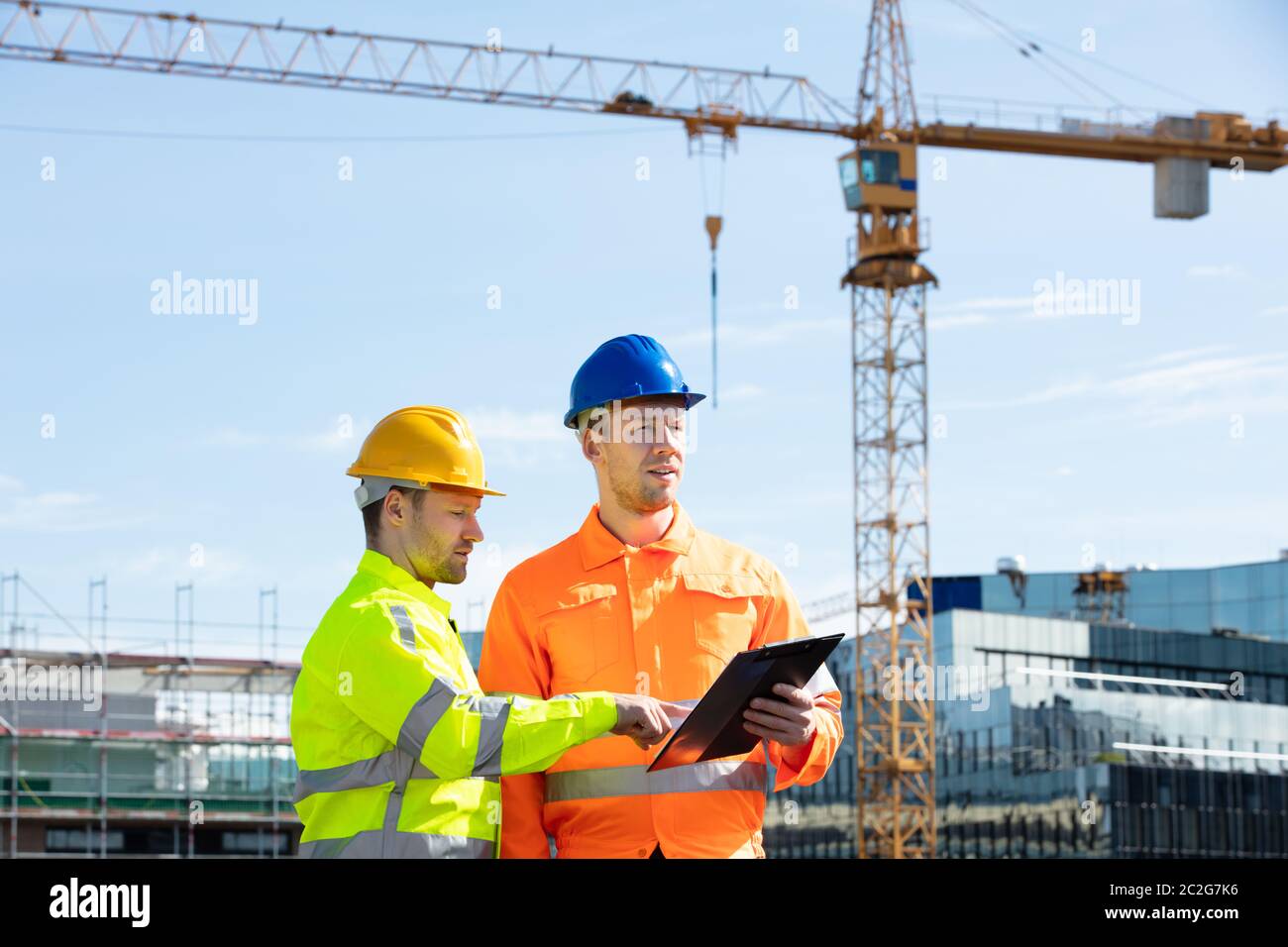 Male Architect Giving Instructions To His Foreman On Clipboard Working ...
