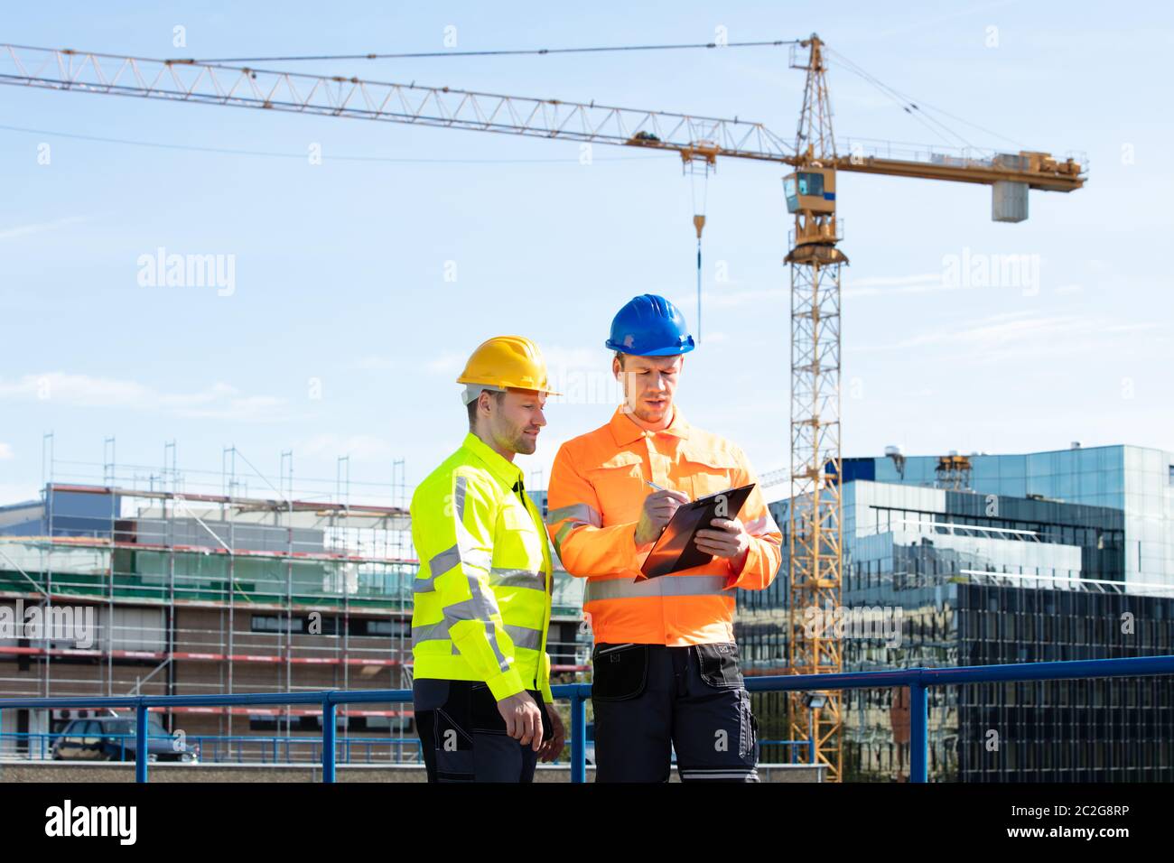 Male Architect Giving Instructions To His Foreman On Clipboard Working ...