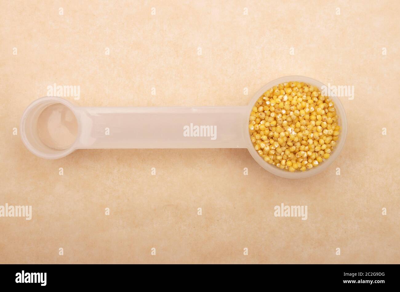 Raw millet in measuring spoon on brown background Stock Photo - Alamy