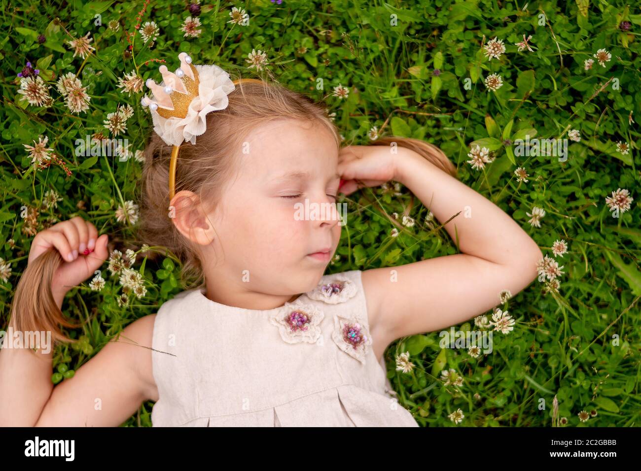 Sweet little girl sleeping on a green grass. girl lying on the grass ...