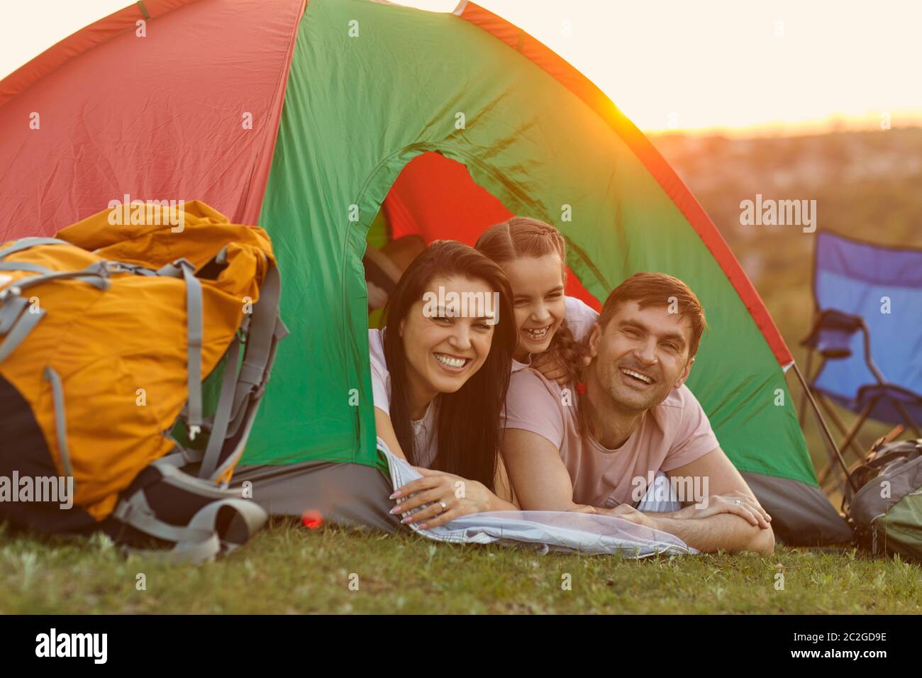 Happy family with child on camping trip relaxing inside tent. Caring ...