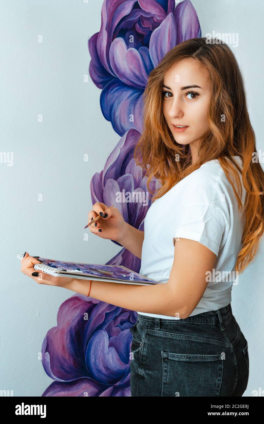 Artist. Designer. Young girl artist paints on a wall indoors. Interior ...