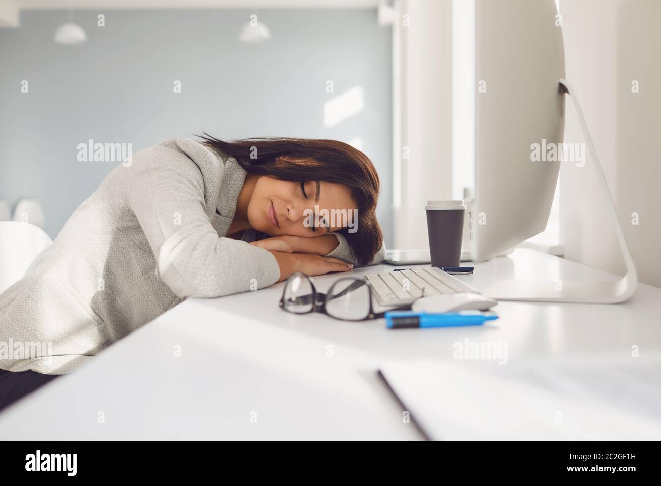 Tired business woman lies asleep at the desk workplace in the office ...