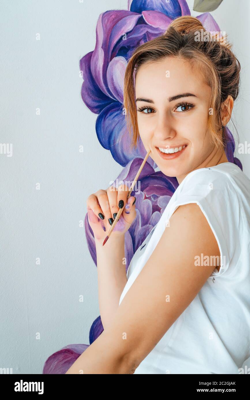 Artist. Designer. Young girl artist paints on a wall indoors. Interior ...