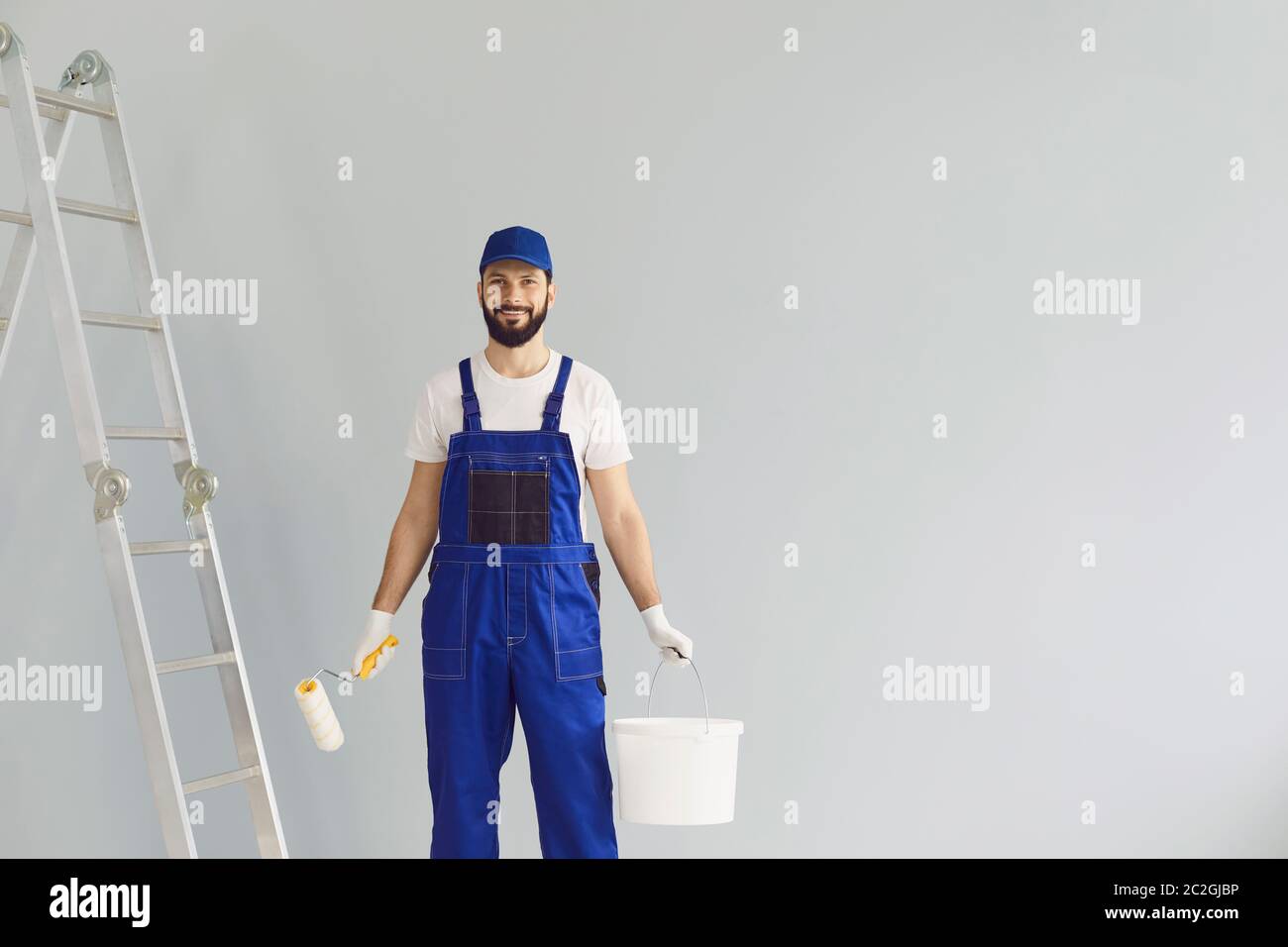 Painter worker holding roller brush and bucket with paint Stock Photo ...