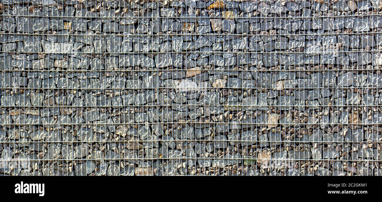 Gabion, a stone wall with a metal grid of gray granite texture Stock ...