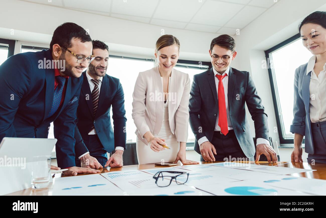 Team of business people analyzing numbers and charts spread out on the ...