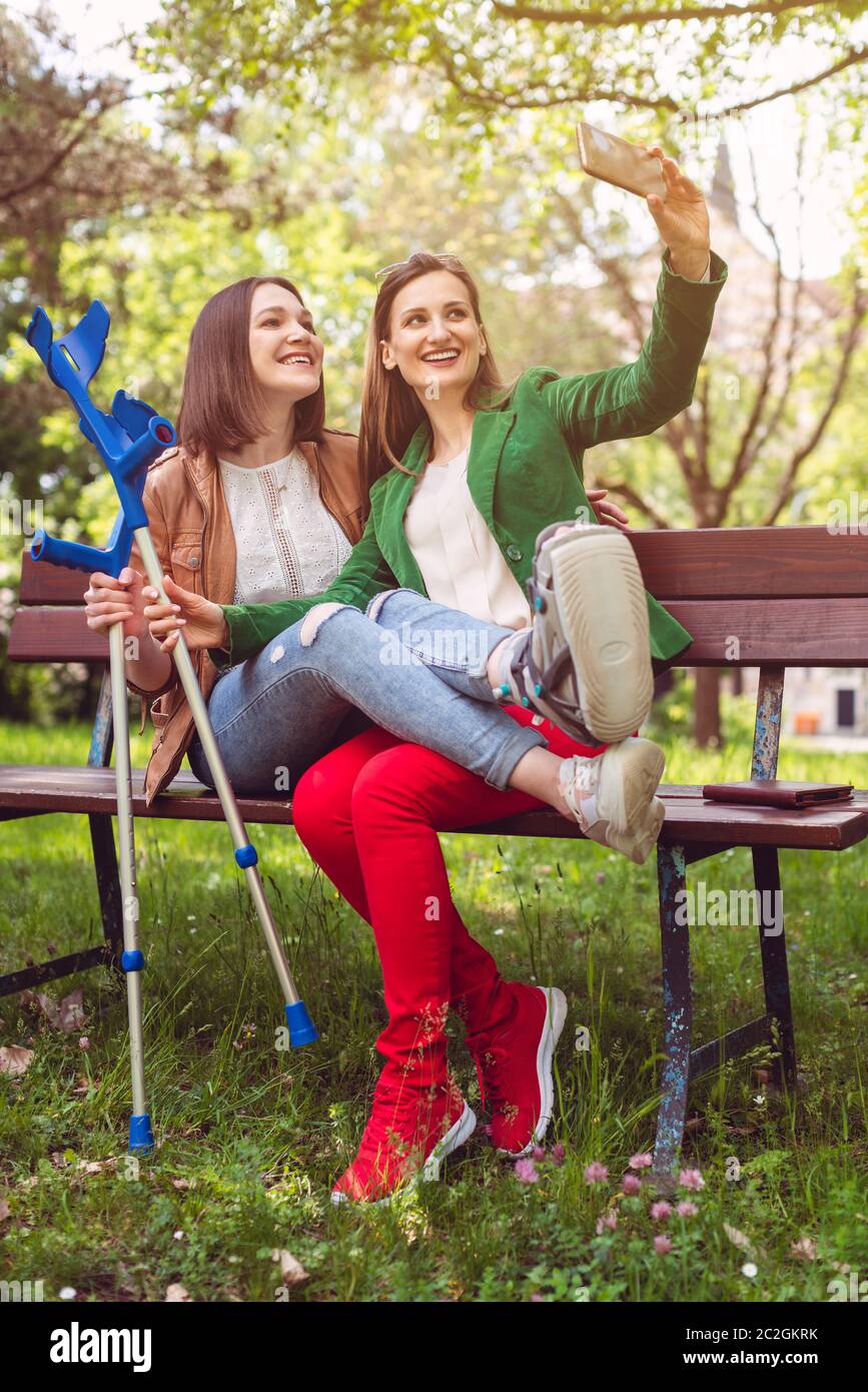 Woman and her friend with a sprained ankle taking a photo or selfie ...