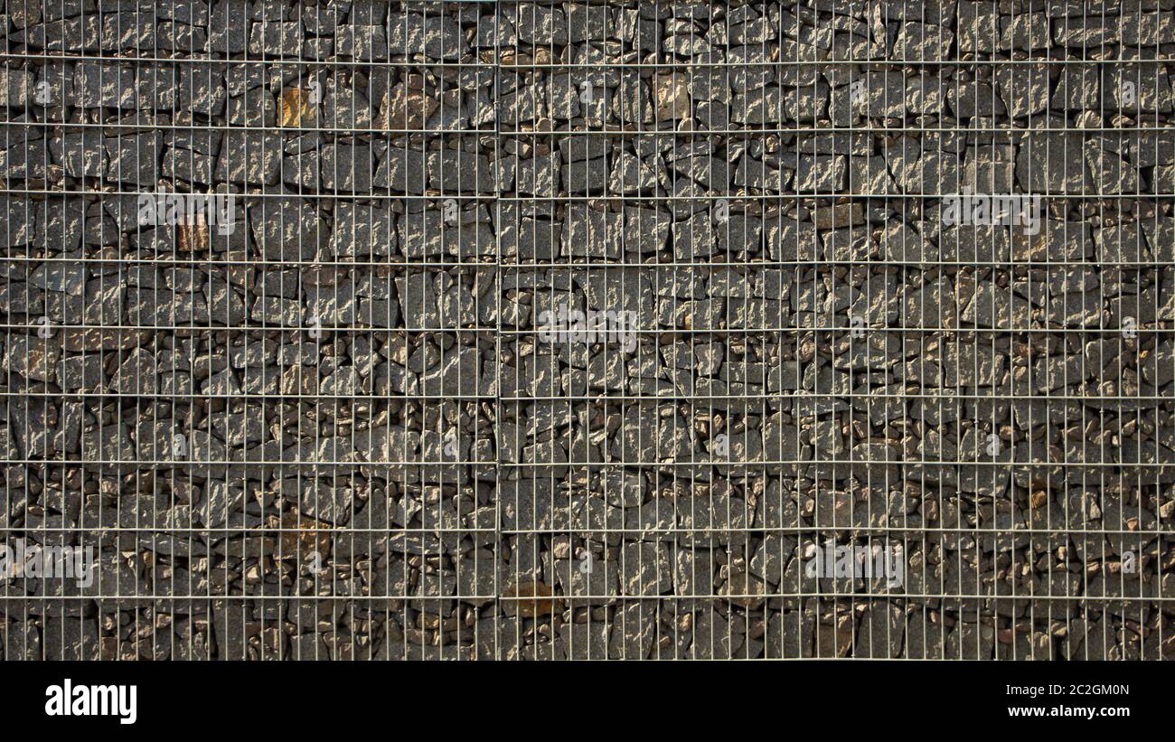 Gabion, a stone wall with a metal grid of gray granite texture Stock ...