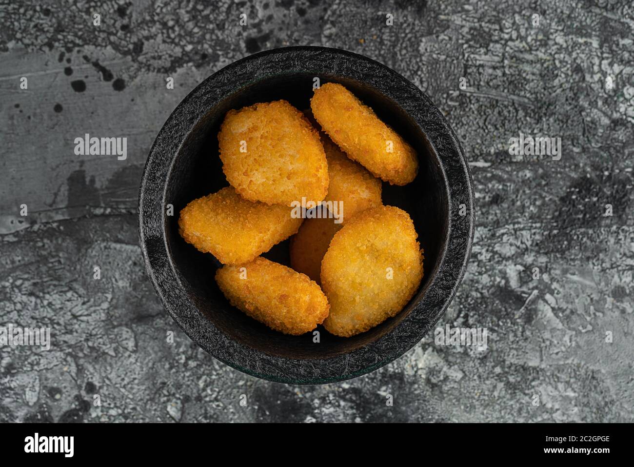 A portion of delicious and crispy chicken nuggets on grey background. A ...