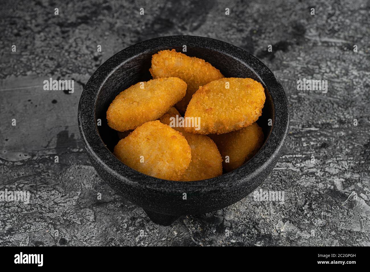 A portion of delicious and crispy chicken nuggets on grey background. A ...