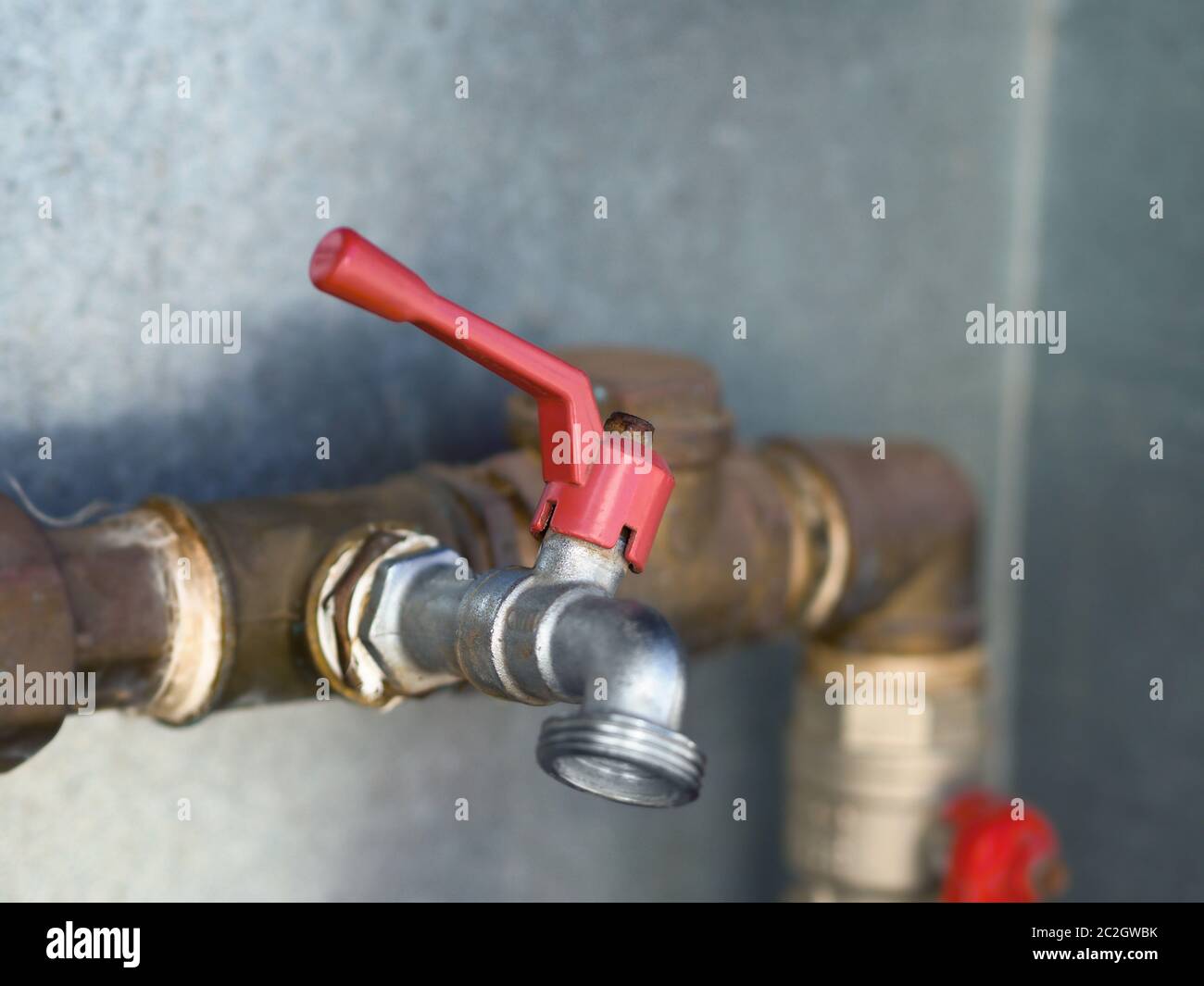 The red handle on a water pipe controls the water inlet. Gold and ...