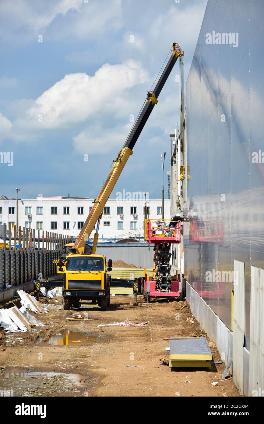 Builders work at a construction site with a cradle of a tower crane ...