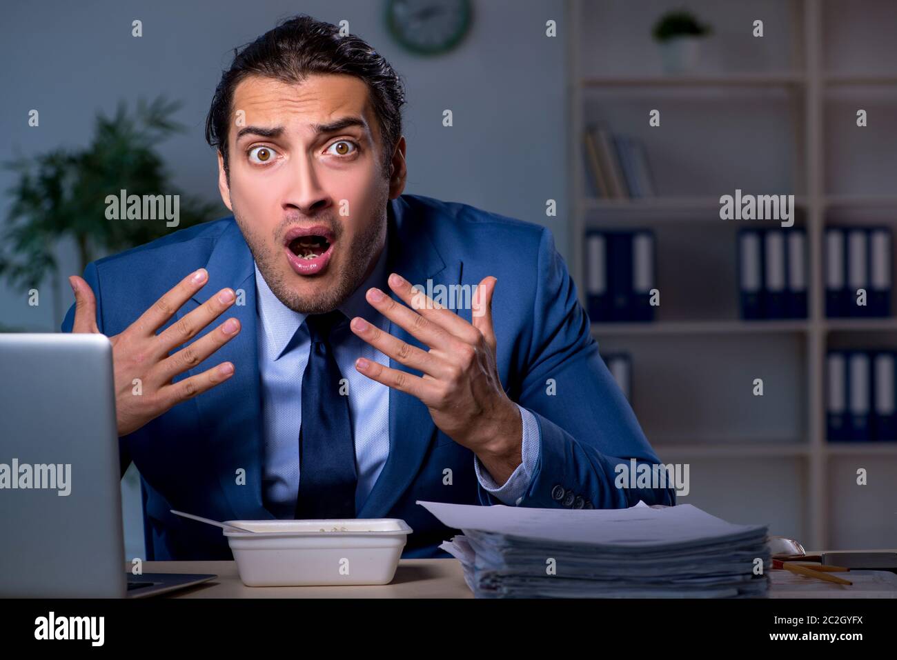 Hungry employee working late in office Stock Photo - Alamy