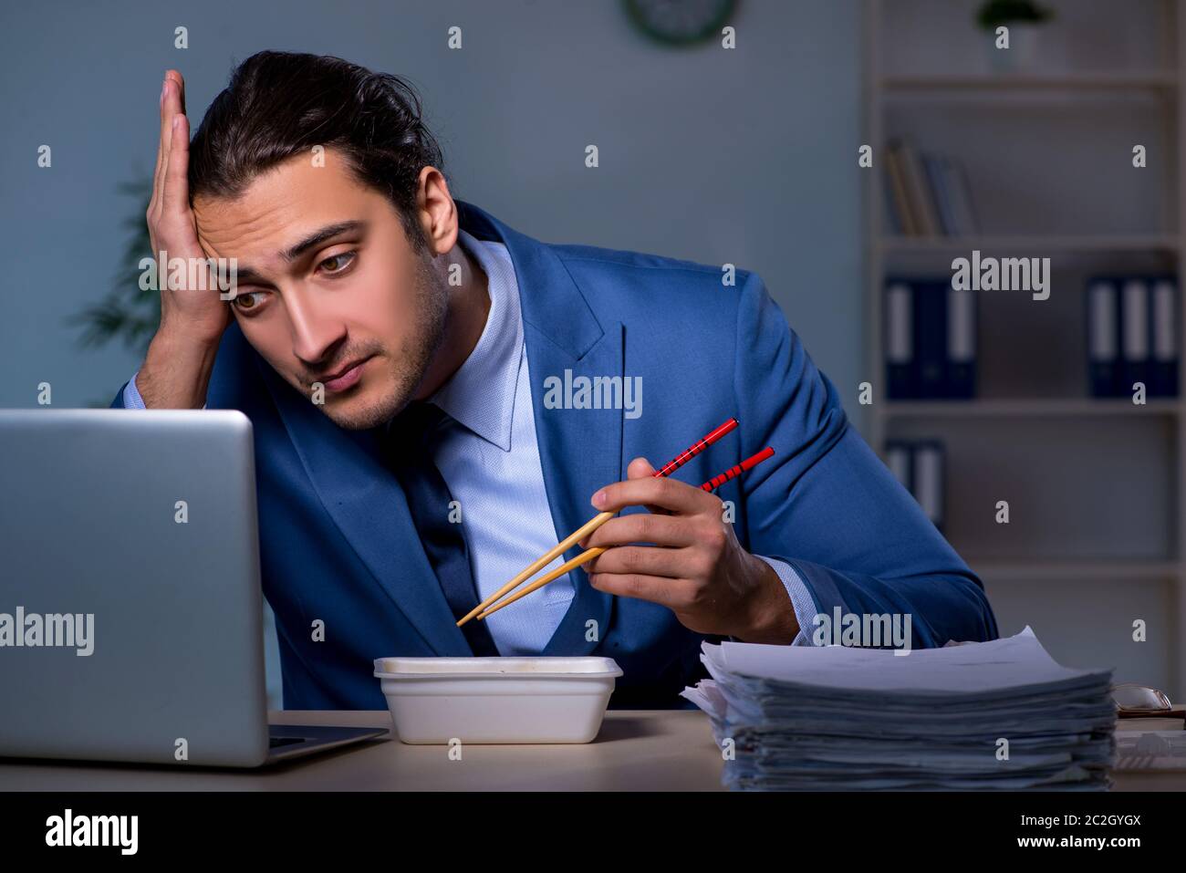 Hungry employee working late in office Stock Photo - Alamy