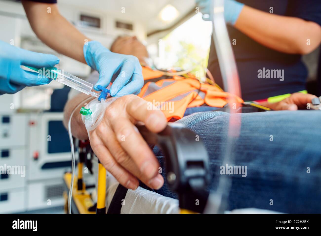Emergency doctor administering injection needle in ambulance, closeup ...