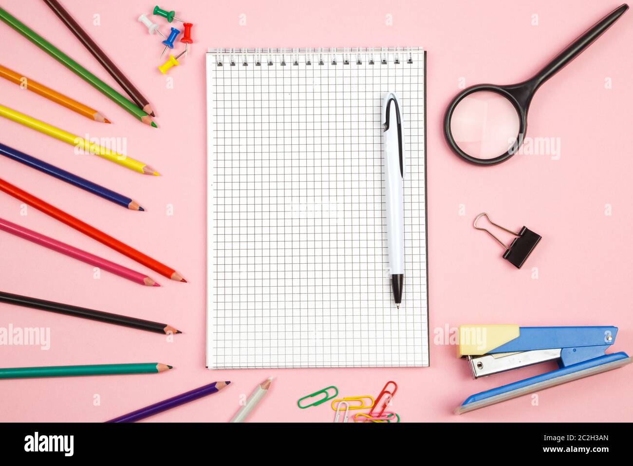 colored pencils, stationery, paper notebook with pen and magnifier on ...
