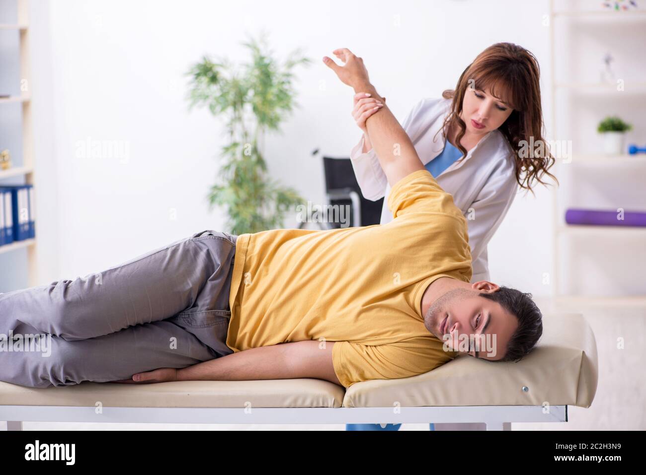 Injured man visiting female doctor osteopath Stock Photo - Alamy