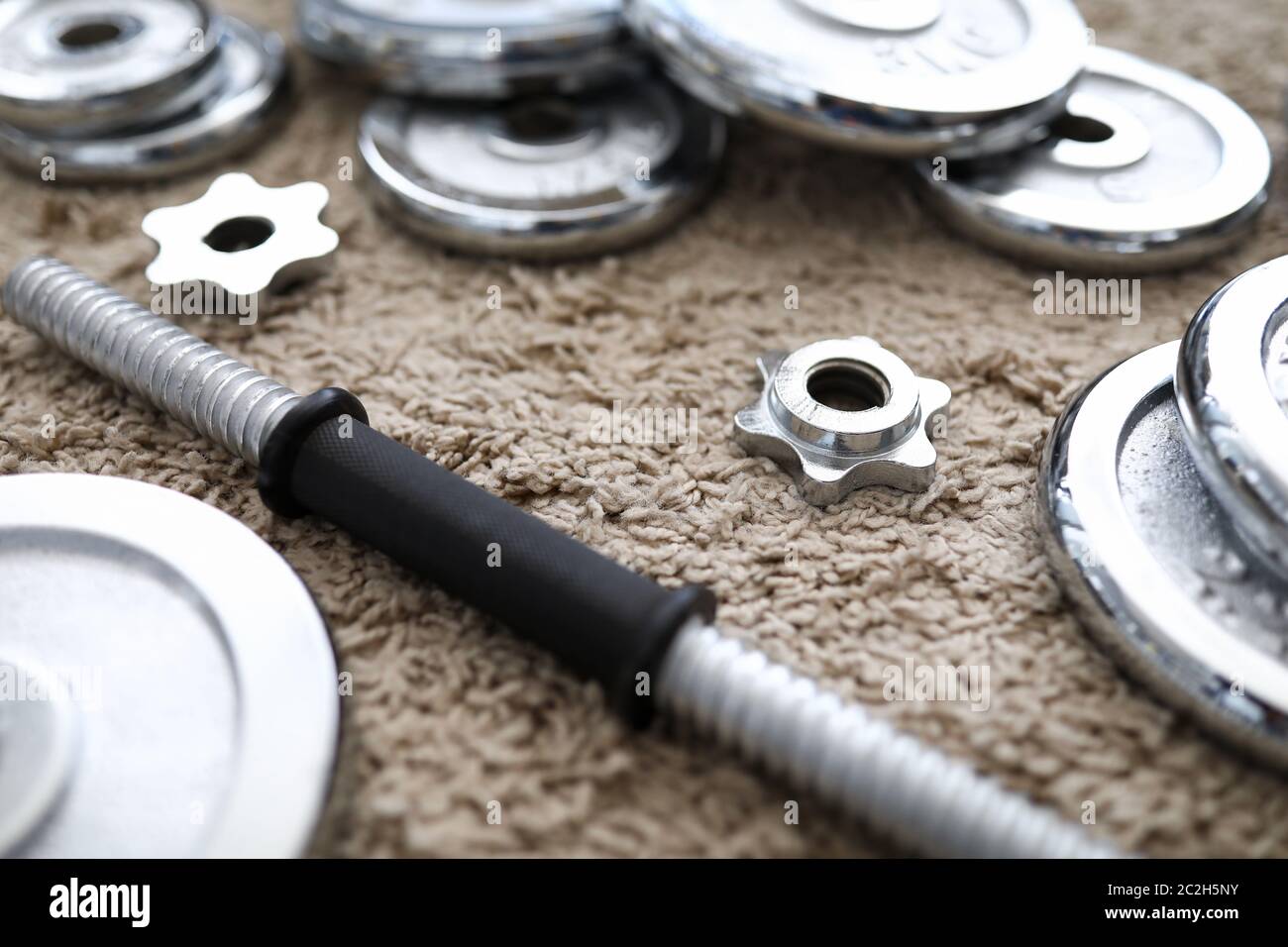 Pile of shiny chrome dumbbells disks lying around grip Stock Photo - Alamy